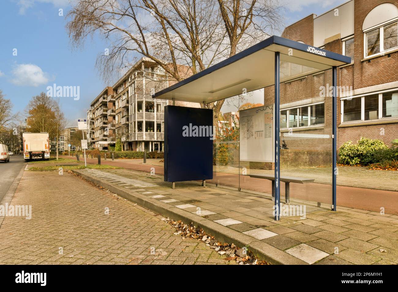 a bus stop on the side of a street in front of a building with trees ...