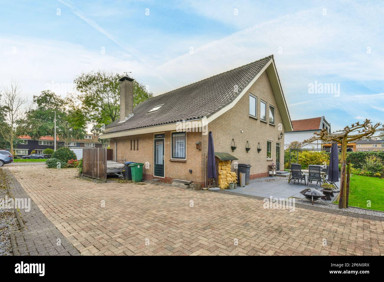 a brick house with a car parked in the driveway and two cars parked on ...