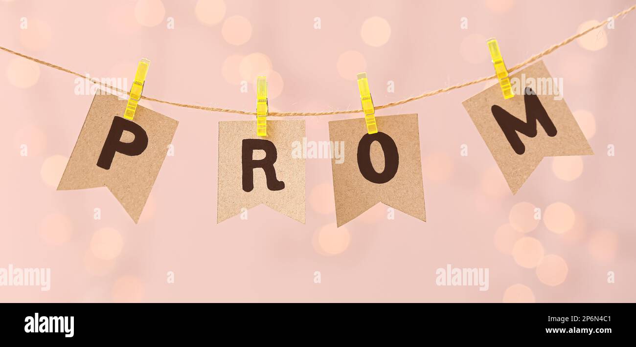 Rope, clothespins and paper flags with word PROM against blurred lights ...