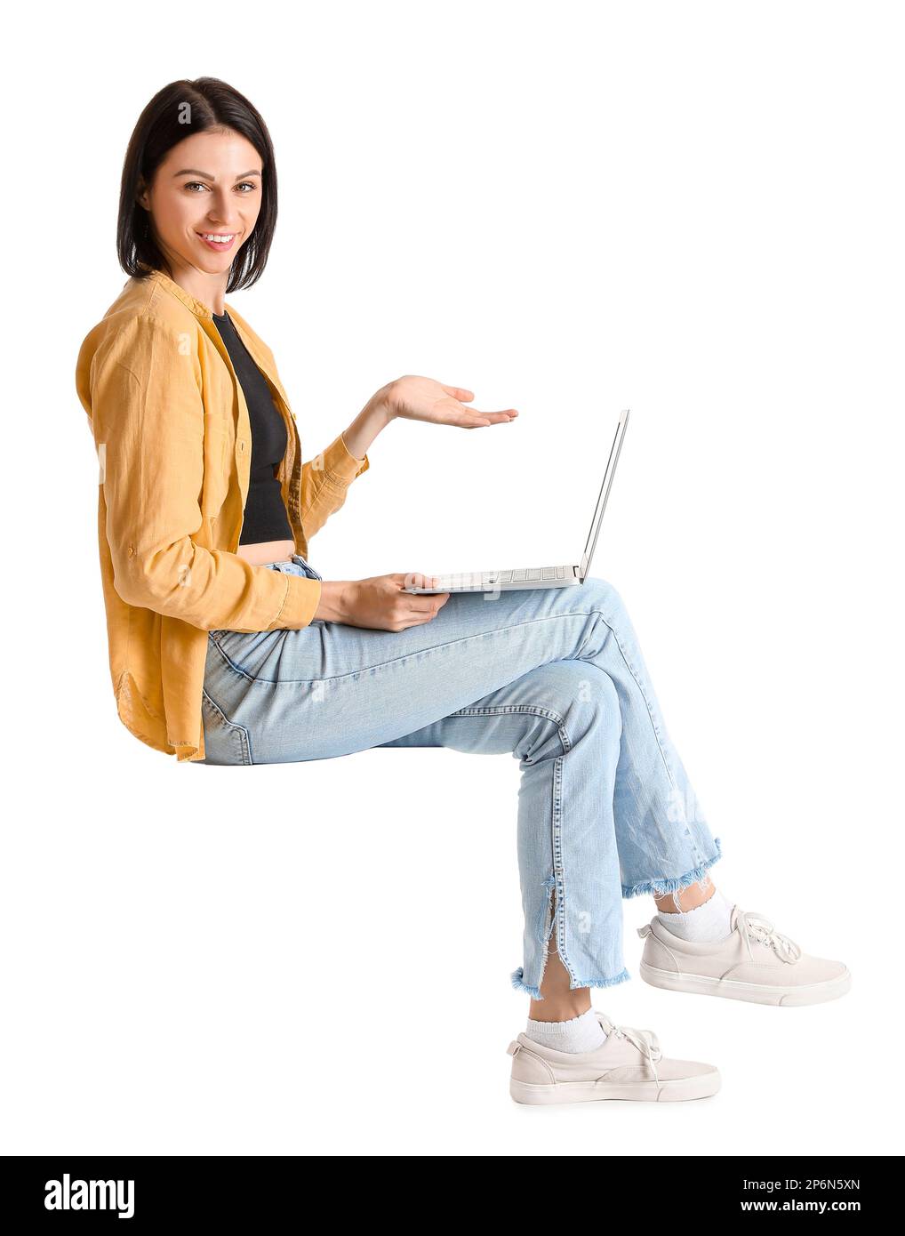 Pretty young woman with laptop sitting on chair against white ...