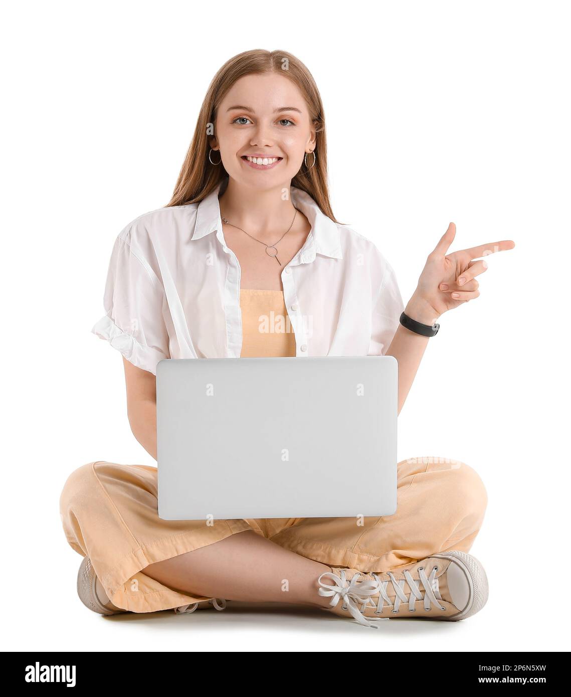 Beautiful girl with laptop pointing at something on white background ...