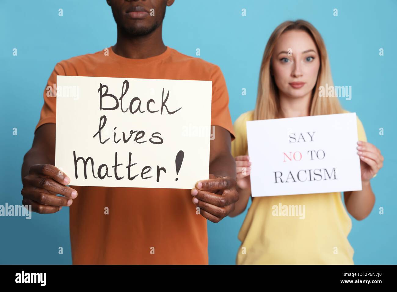 Young woman and African American man holding signs on light blue ...