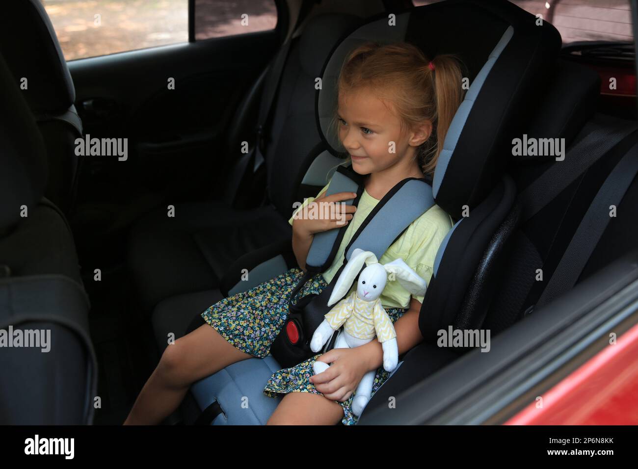Cute little girl sitting in child safety seat inside car Stock Photo ...