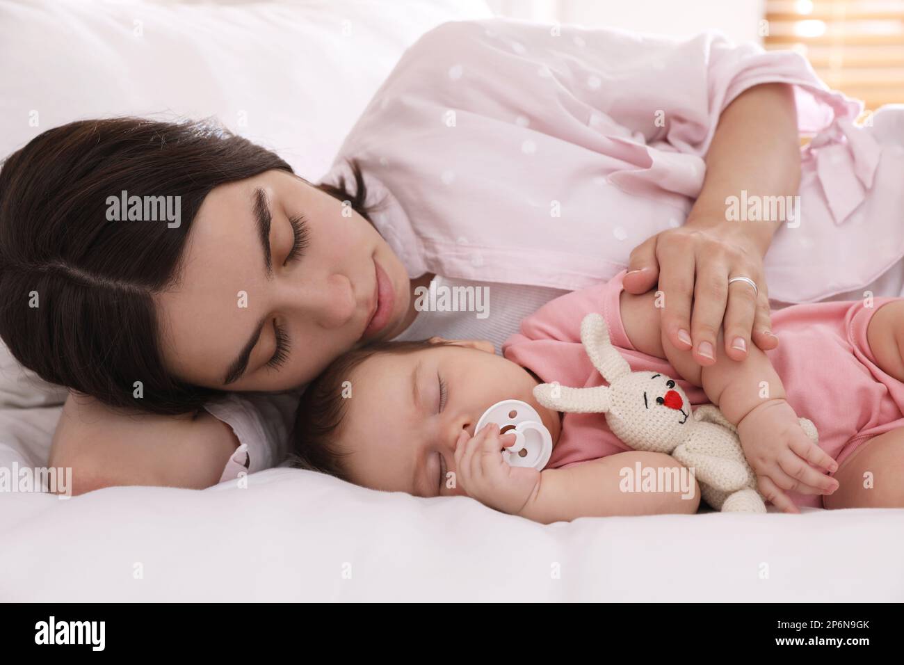 Young mother resting near her sleeping baby on bed Stock Photo - Alamy