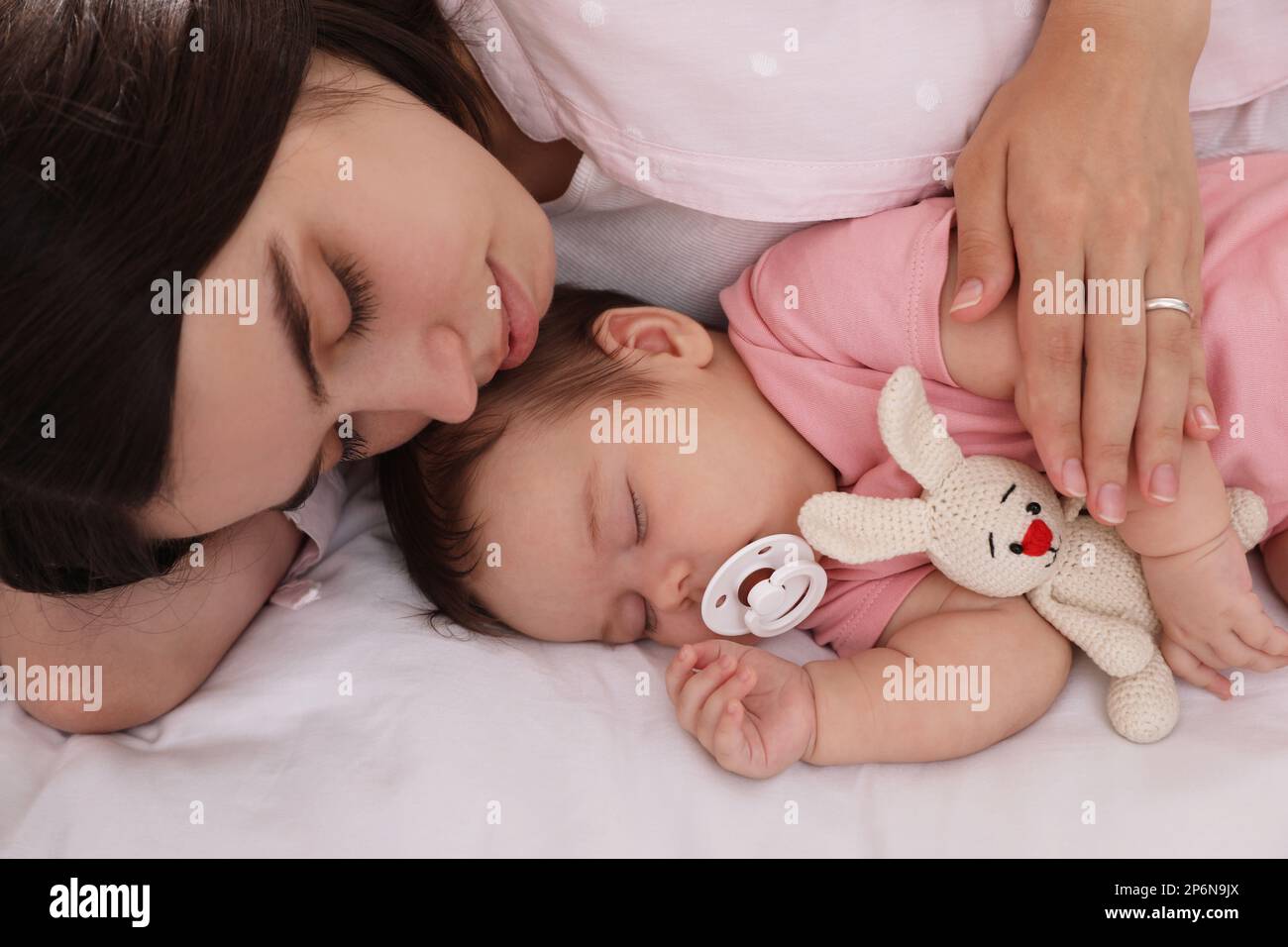Young mother resting near her sleeping baby on bed, closeup Stock Photo ...
