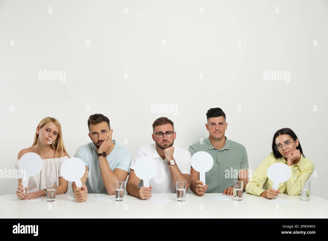 Panel of disappointed judges holding blank score signs at table on ...