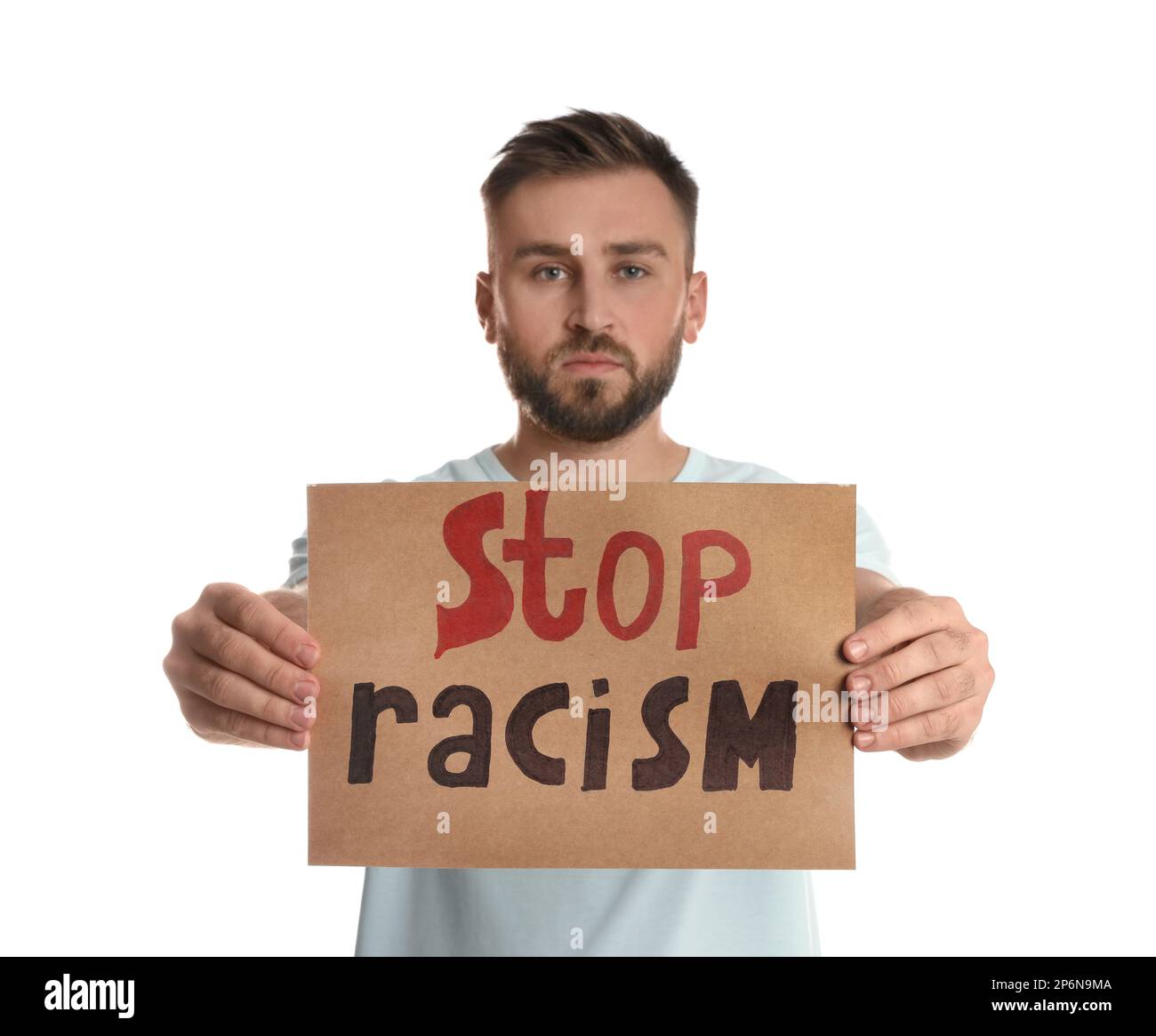 Young man holding sign with phrase Stop Racism on white background ...