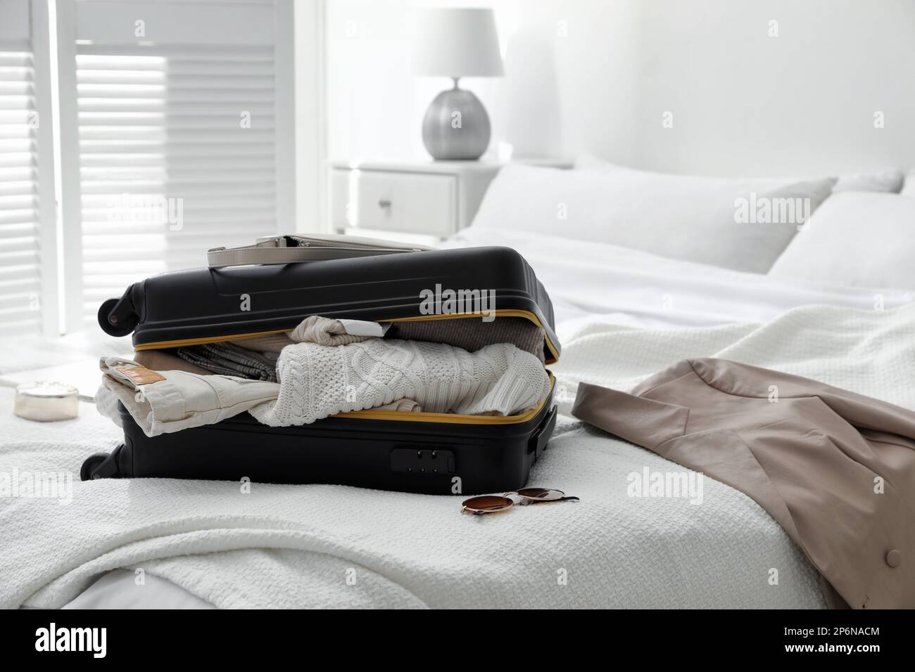 Open suitcase full of clothes, jacket and fashionable accessories on ...