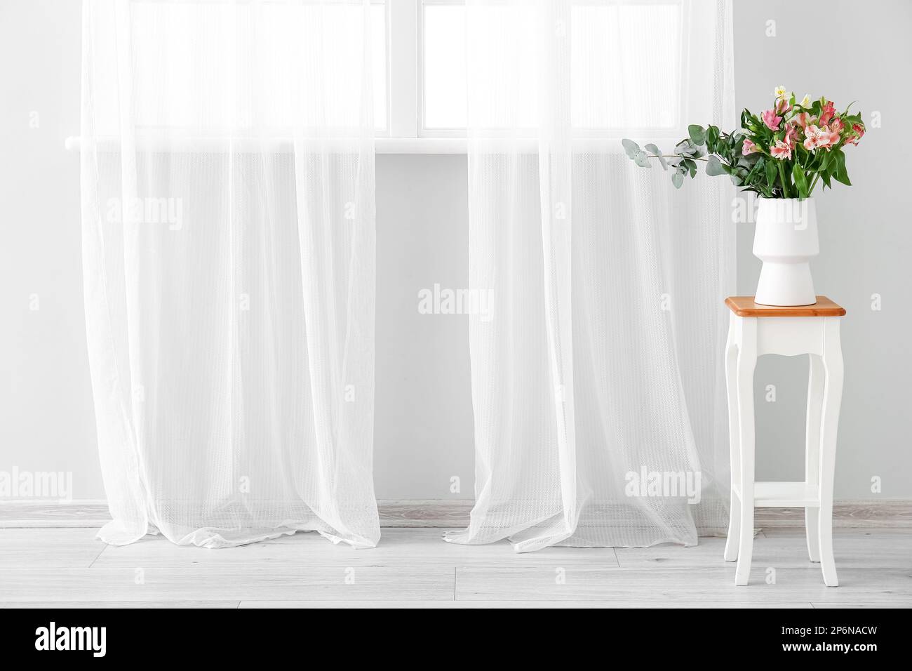 Vase with beautiful alstroemeria flowers on stool in light room Stock ...