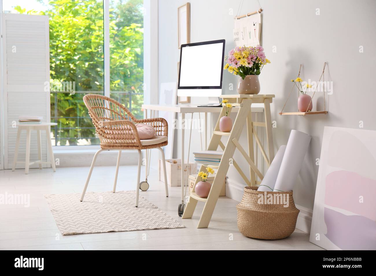 Comfortable workplace with modern computer and flowers in room ...