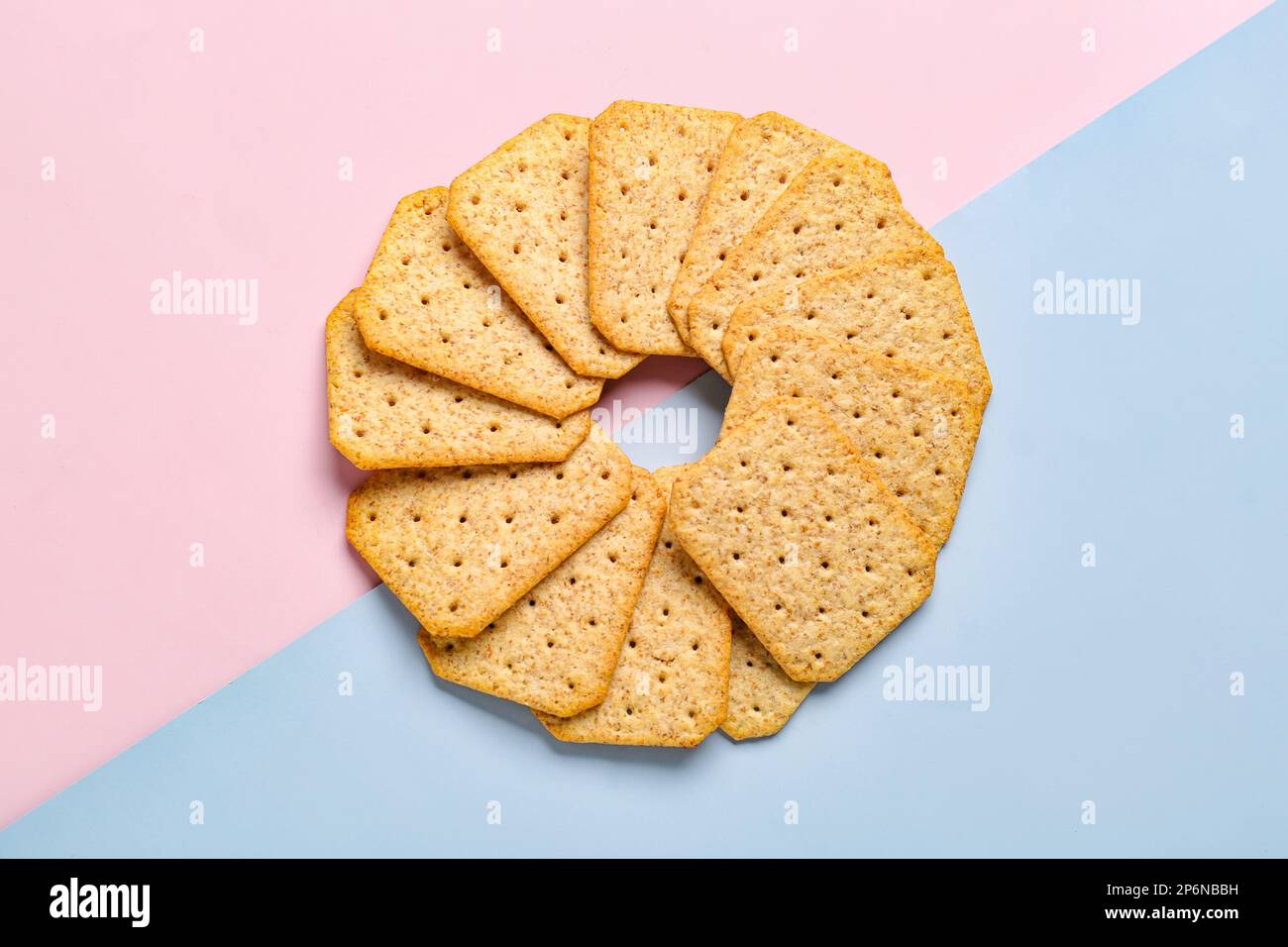 Circle made of delicious crackers on pink and grey background Stock ...