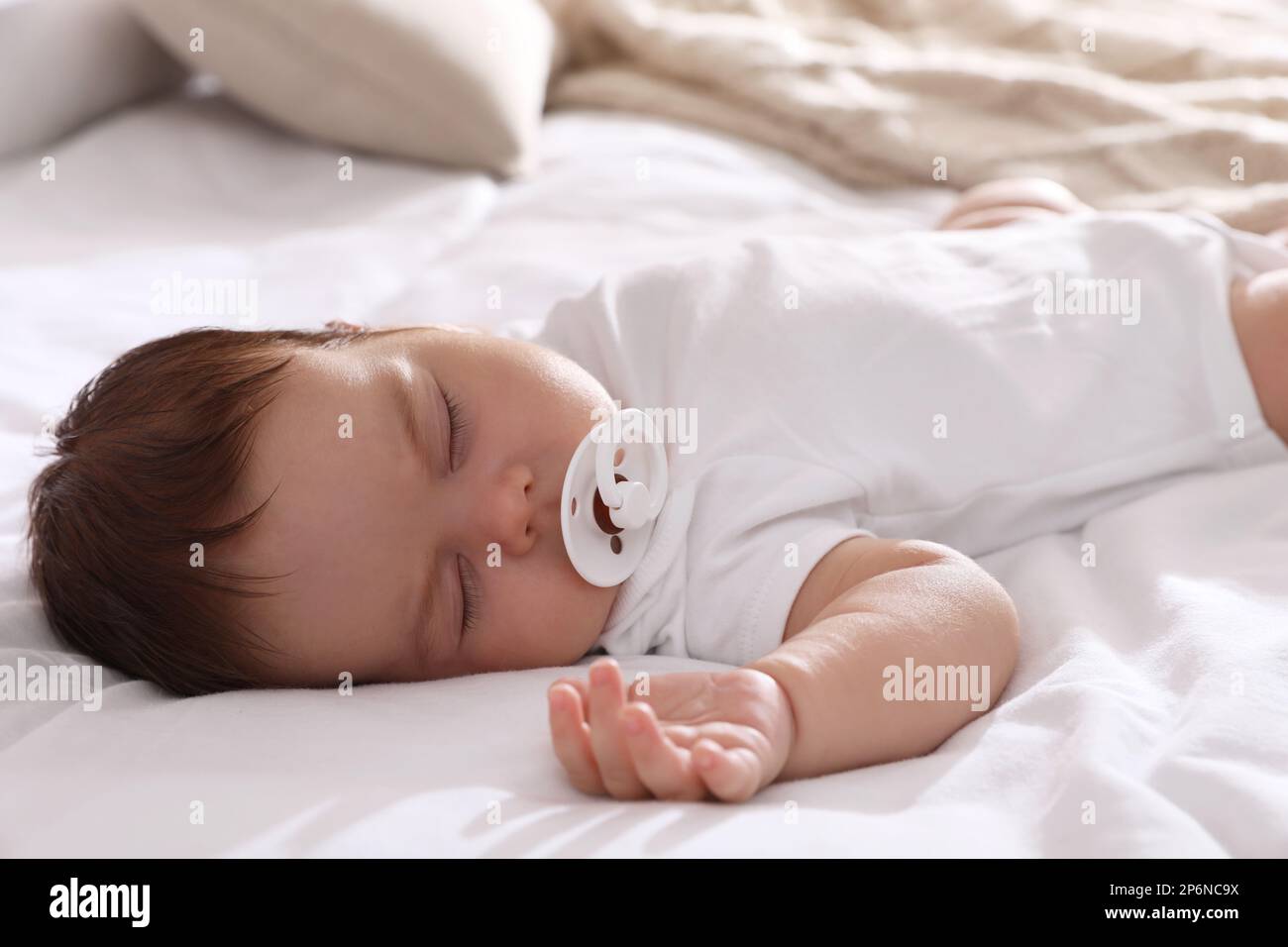 Cute little baby with pacifier sleeping on bed Stock Photo - Alamy