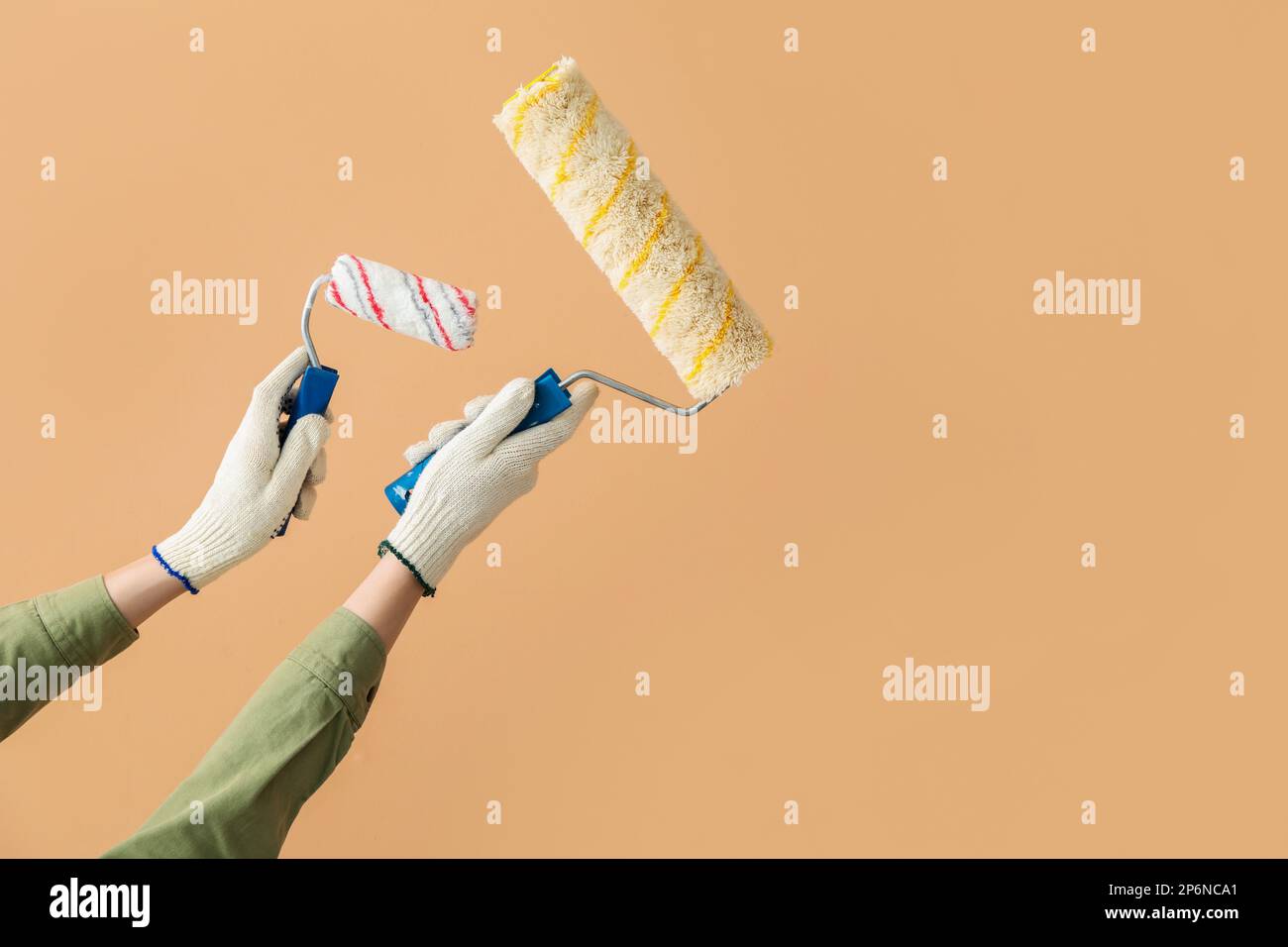 Female painter with rollers on beige background Stock Photo - Alamy