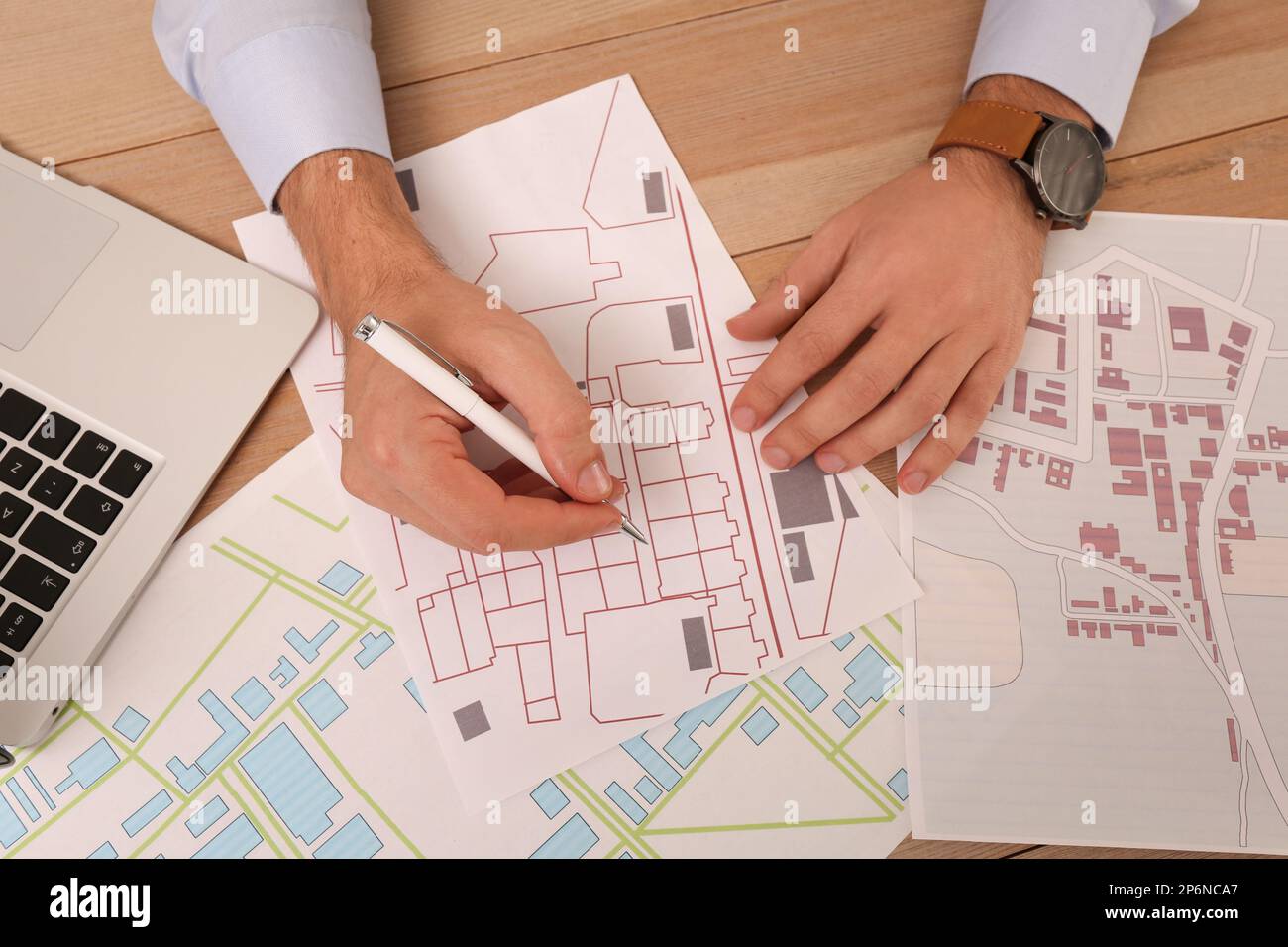 Professional cartographer working with cadastral map at wooden table ...