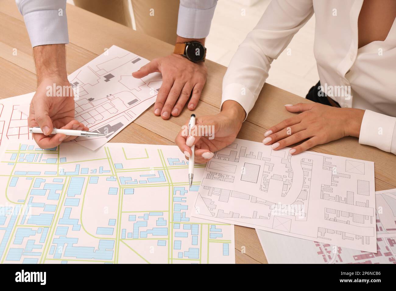 Professional cartographers working with cadastral map at table, closeup ...