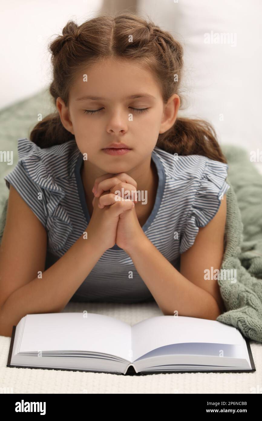 Cute little girl praying over Bible in bedroom Stock Photo - Alamy