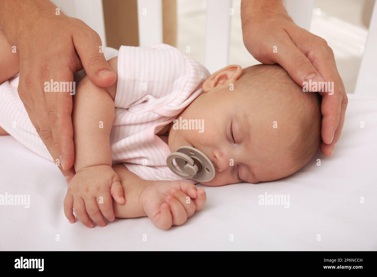Father putting his cute baby into crib Stock Photo - Alamy