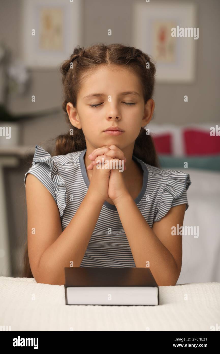 Cute little girl praying over Bible in bedroom Stock Photo - Alamy