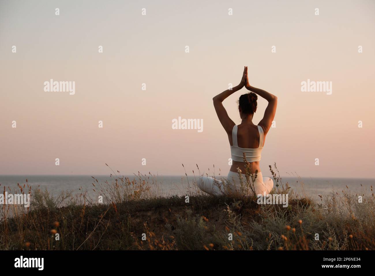 Woman meditating near sea, back view. Space for text Stock Photo - Alamy