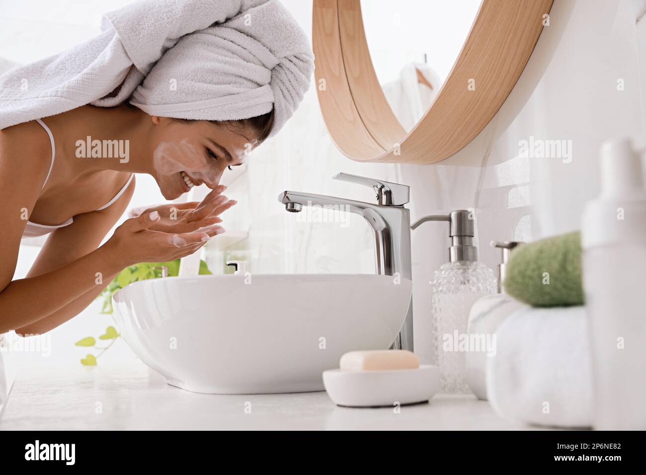 Beautiful teenage girl washing face with cleansing foam in bathroom ...