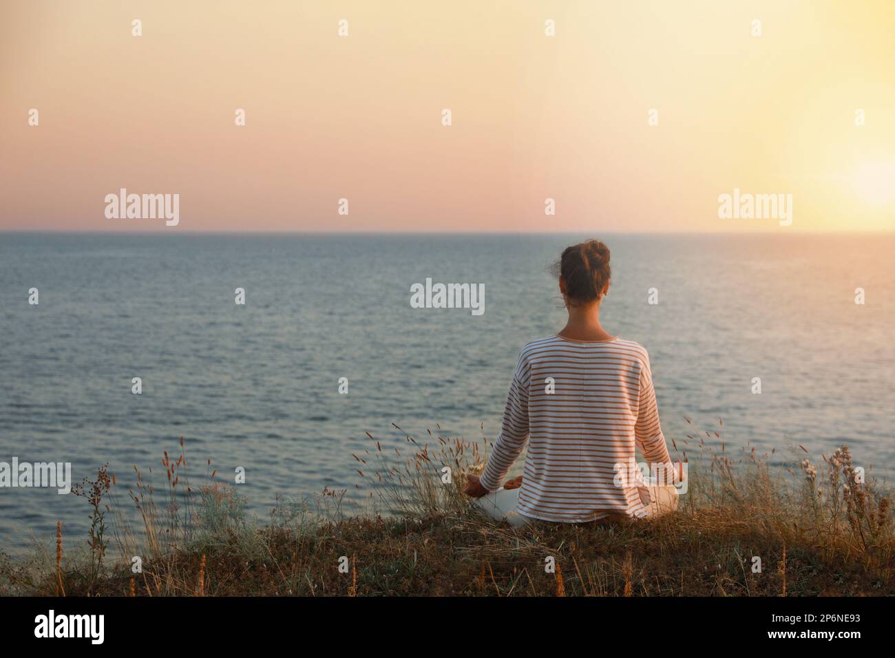 Woman meditating near sea, back view. Space for text Stock Photo - Alamy