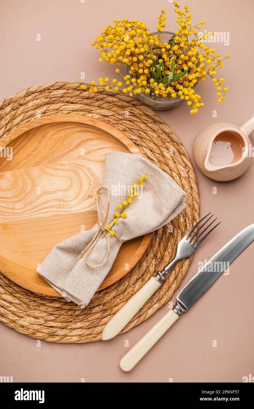 Table setting with wooden plate and beautiful mimosa flowers on beige ...