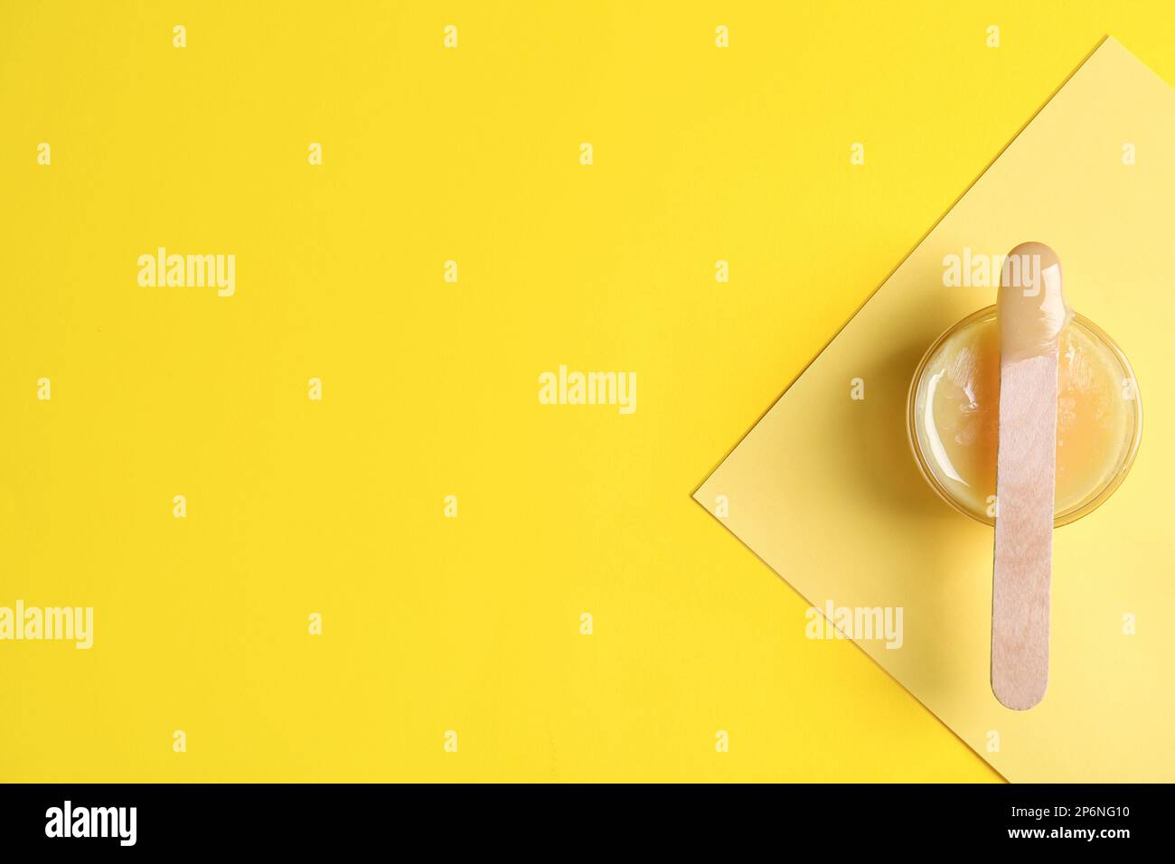 Spatula with wax on yellow background, top view. Space for text Stock ...