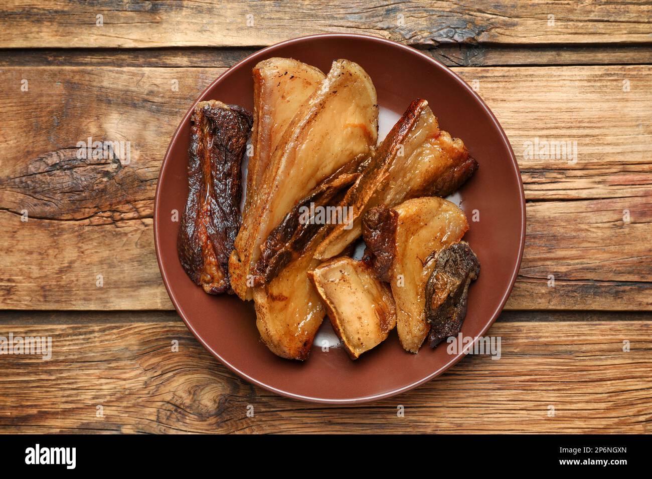 Tasty fried cracklings on wooden table, top view. Cooked pork lard ...