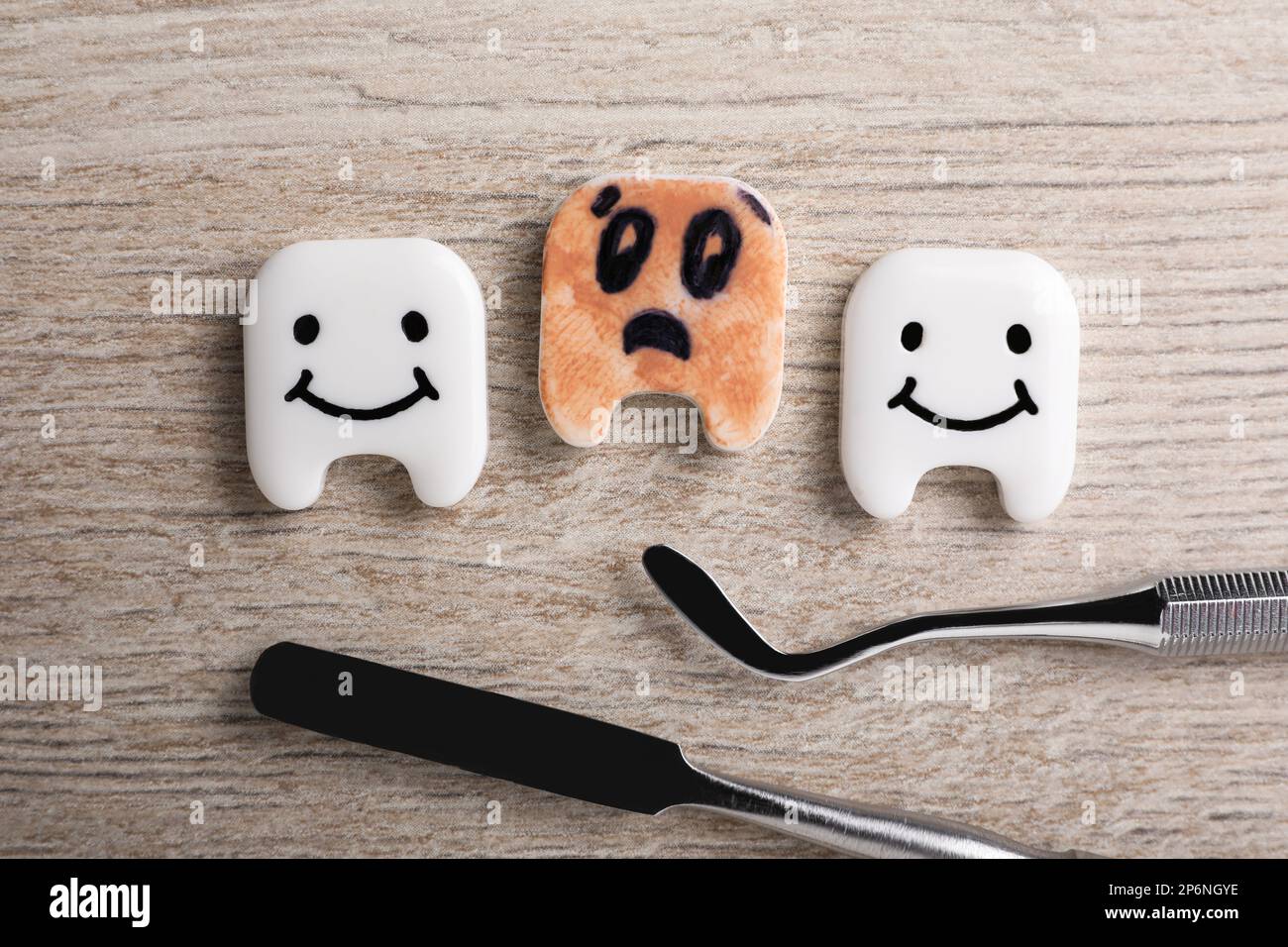 Clean and dirty plastic teeth with faces, dental tools on wooden table ...