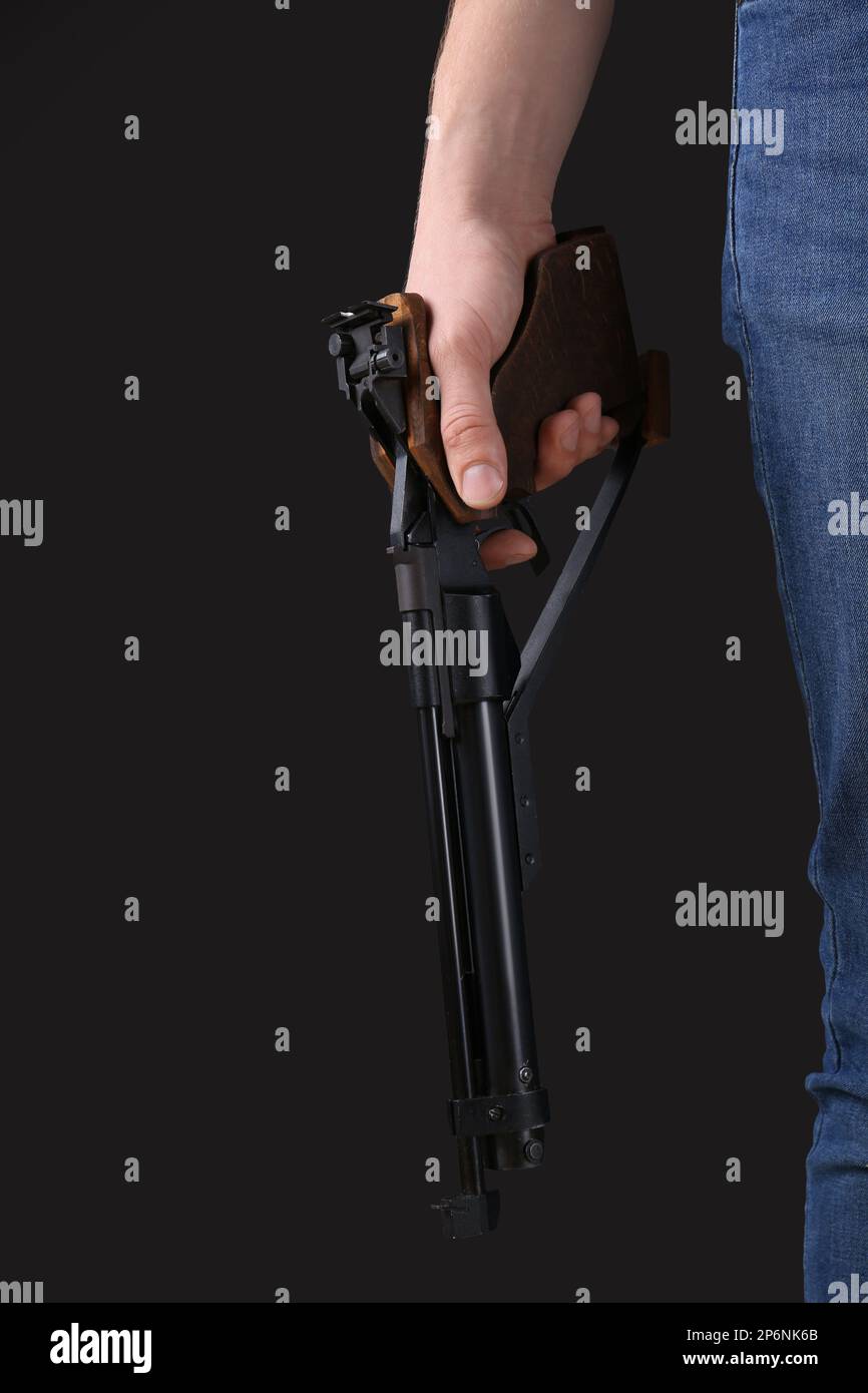 Gun shooting sport. Man holding standard pistol on dark background ...