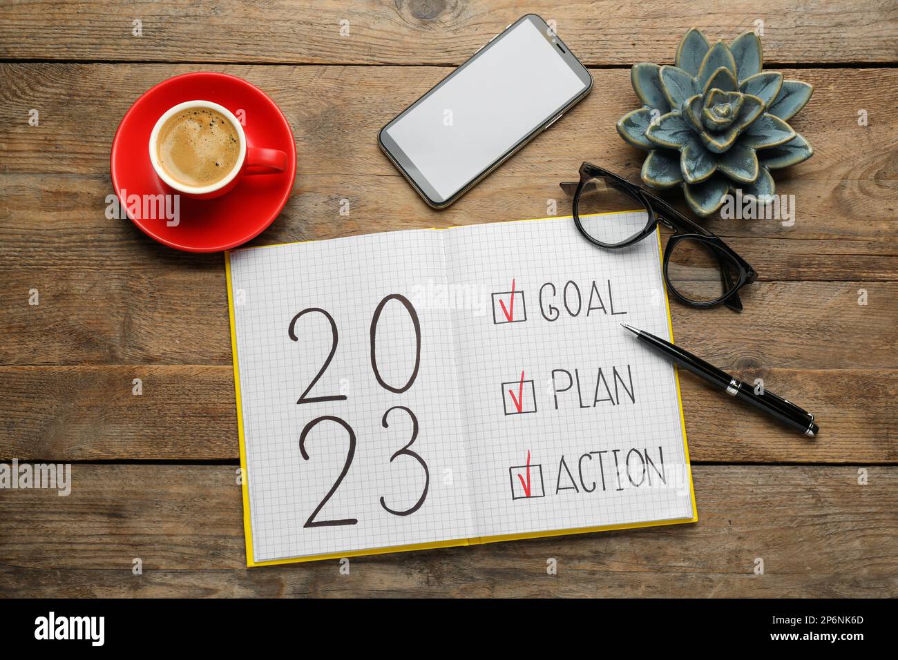 Flat lay composition of notebook with text 2023 Goal, Plan, Action on wooden table. New year ...