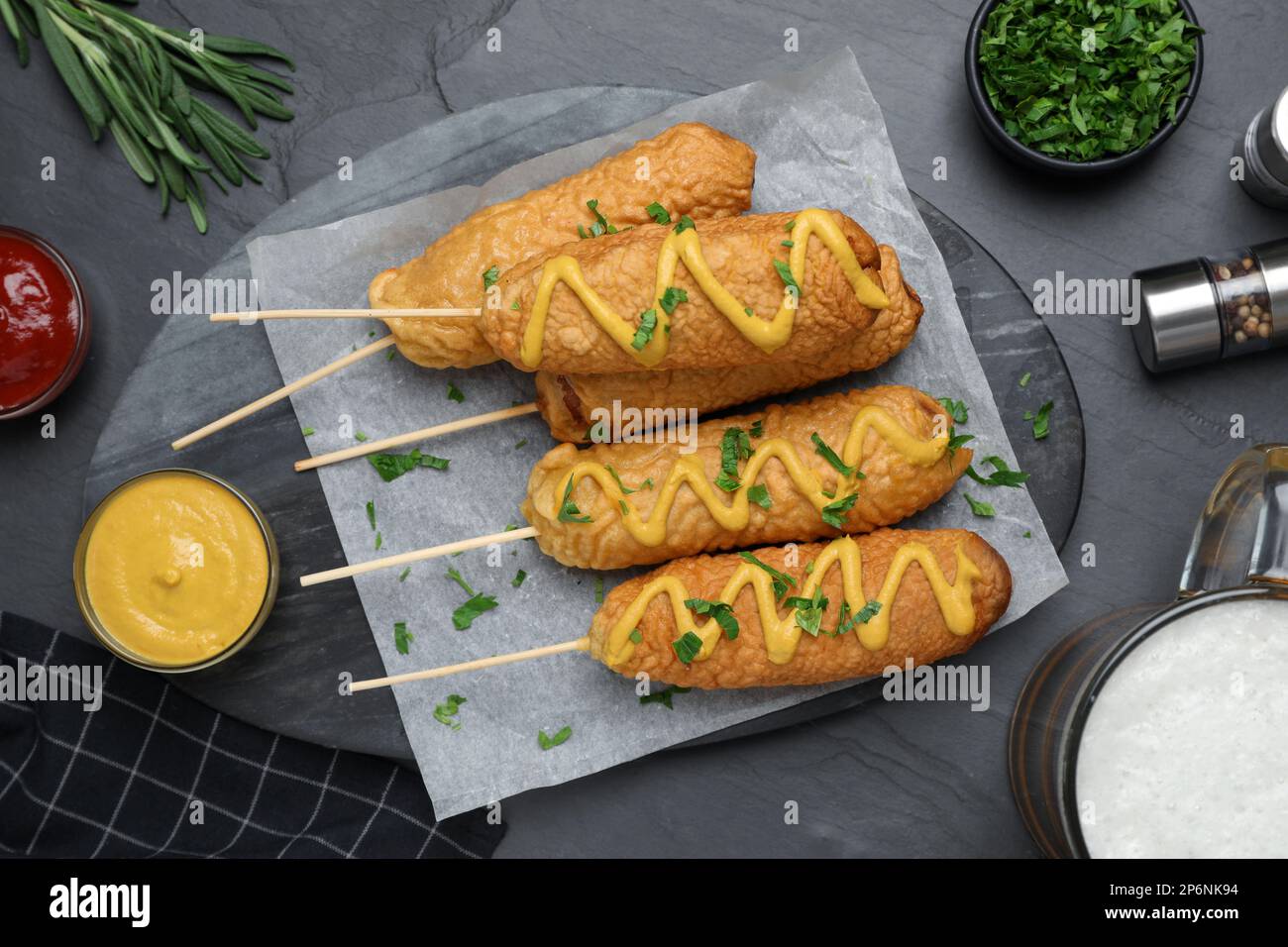 Delicious deep fried corn dogs and sauces on black table, flat lay ...