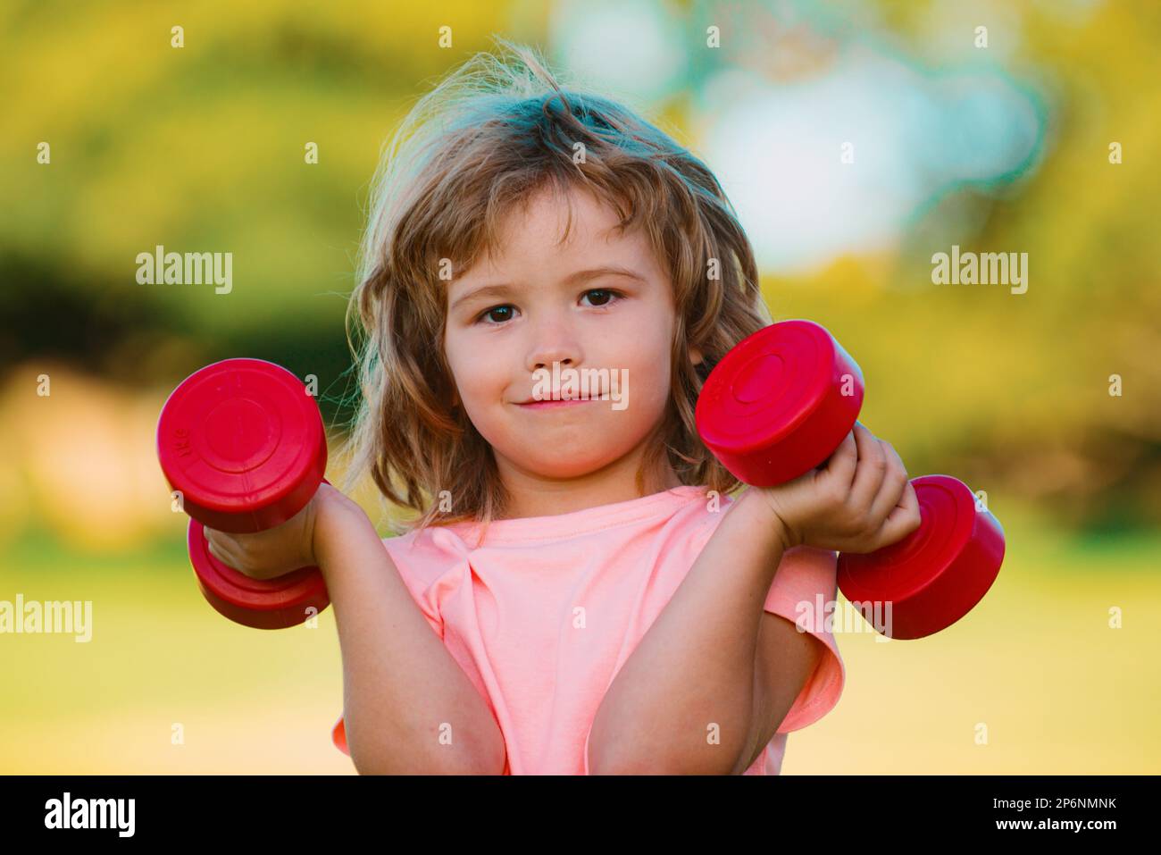 Sport portrait kids. Fitness child. Portrait of sporty little boy with dumbbells in park. Gym ...