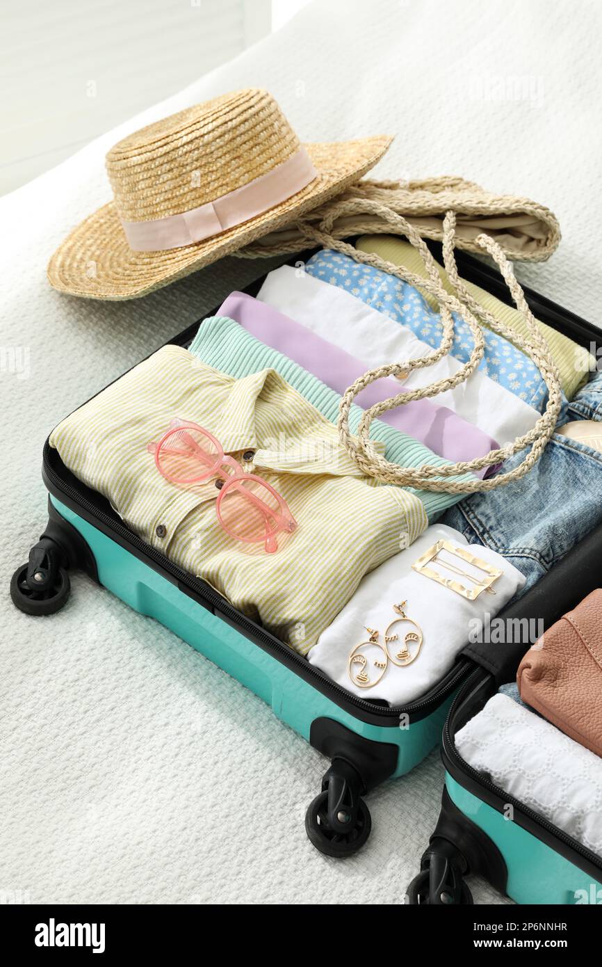 Open suitcase packed for trip and accessories on bed Stock Photo - Alamy