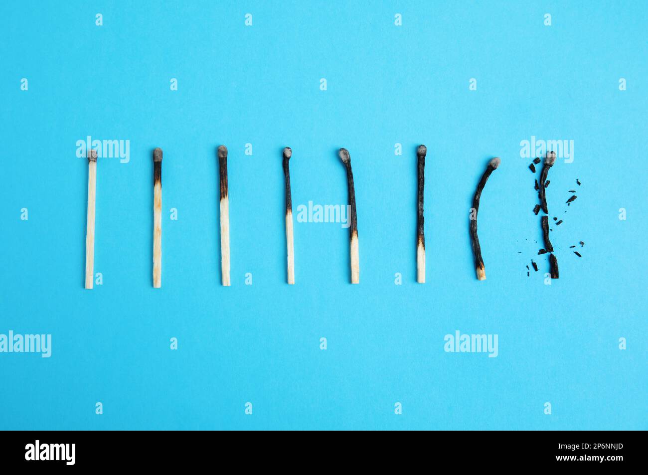 Different stages of burnt matches on light blue background, flat lay ...