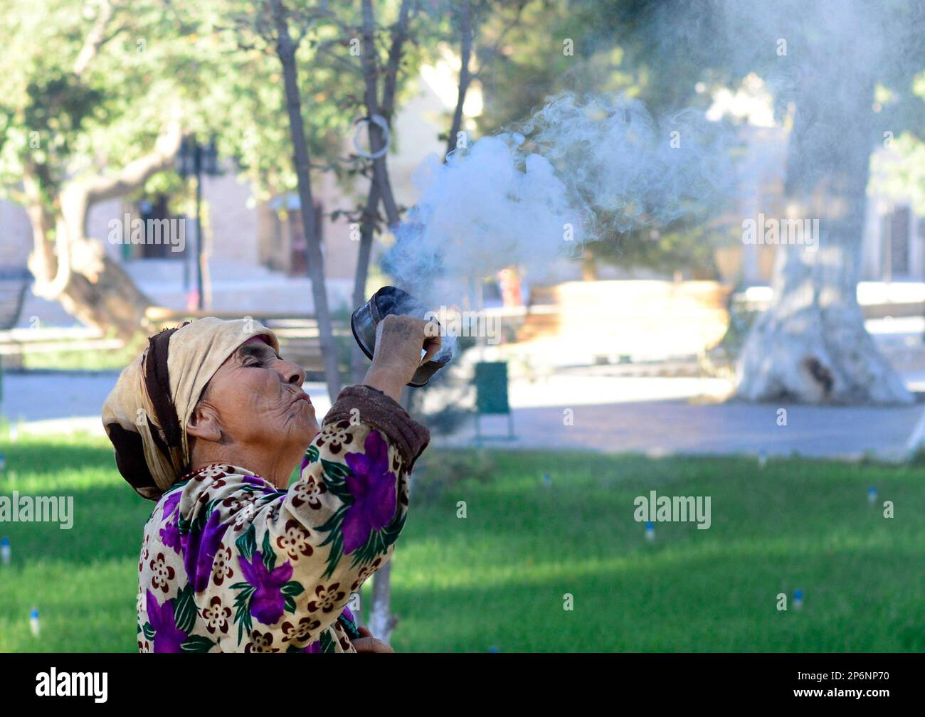 An Uzbek woman blowing smoke as a ritual charm to ward away evil ...