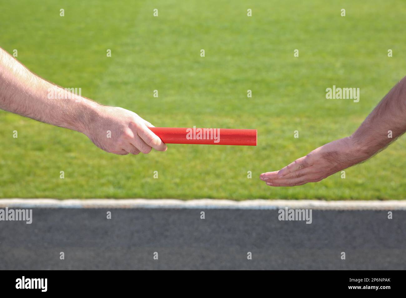 Man passing baton to his partner at stadium, closeup Stock Photo - Alamy