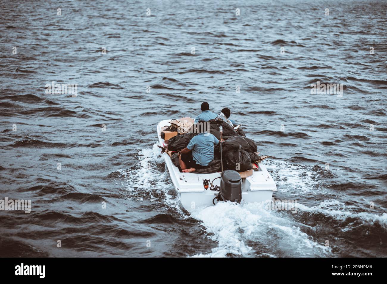 A group of men in a white fisherman's boat is struggling, as the boat ...