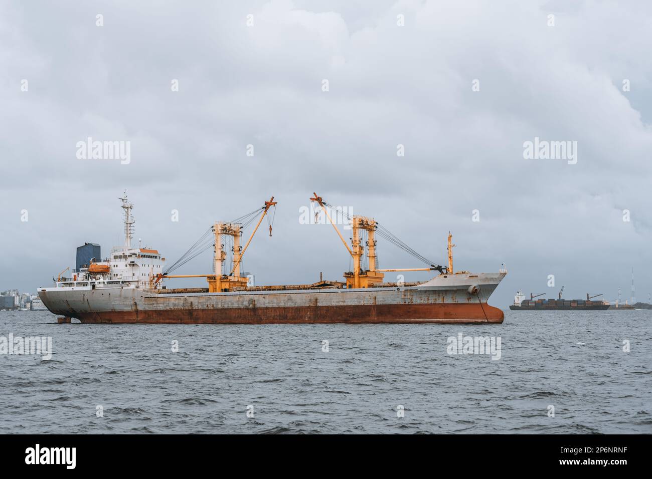 A cargo ship in the serene seas, its worn exterior showing signs of sea ...