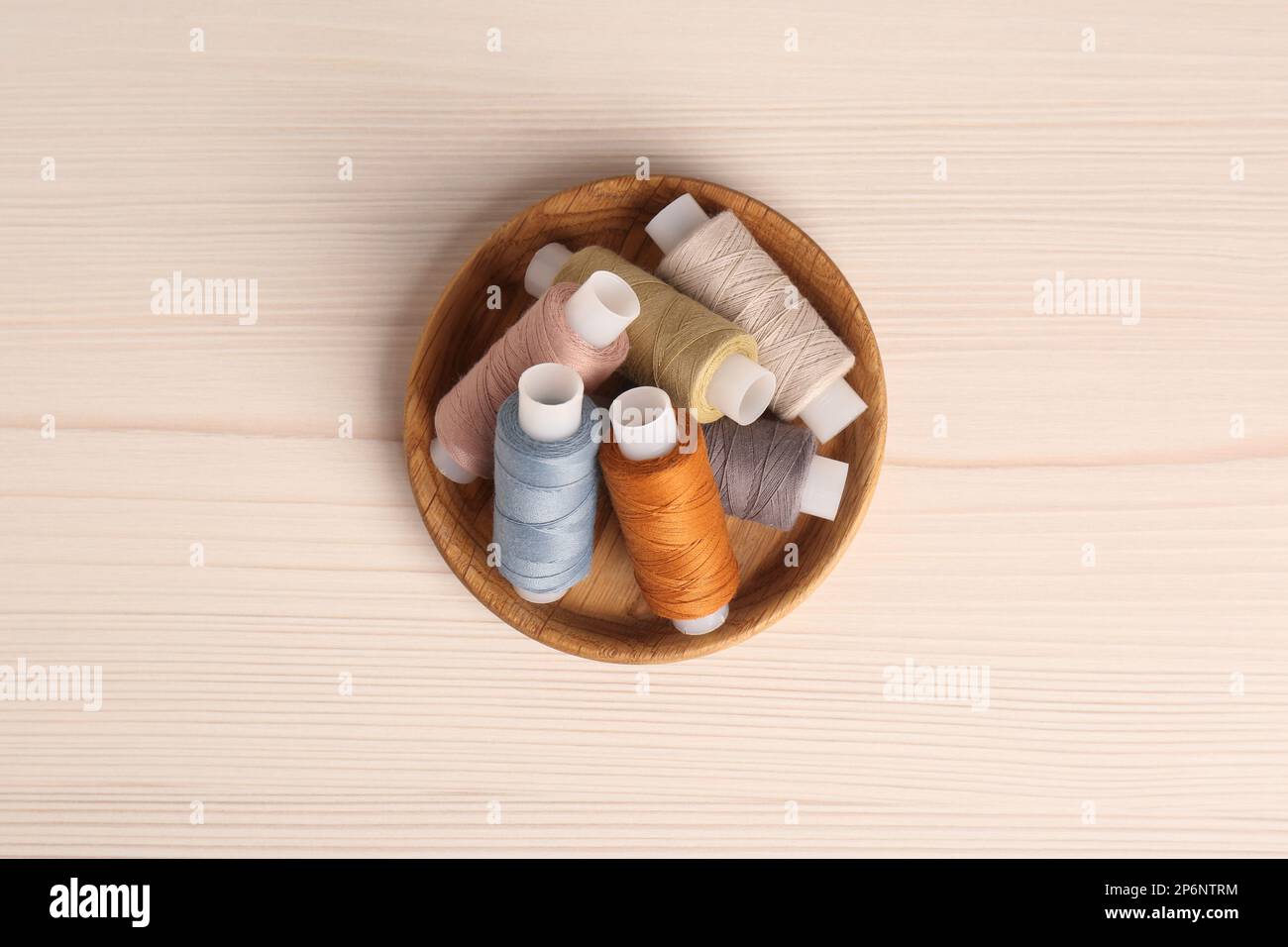 Bowl with color sewing threads on wooden table, top view Stock Photo ...