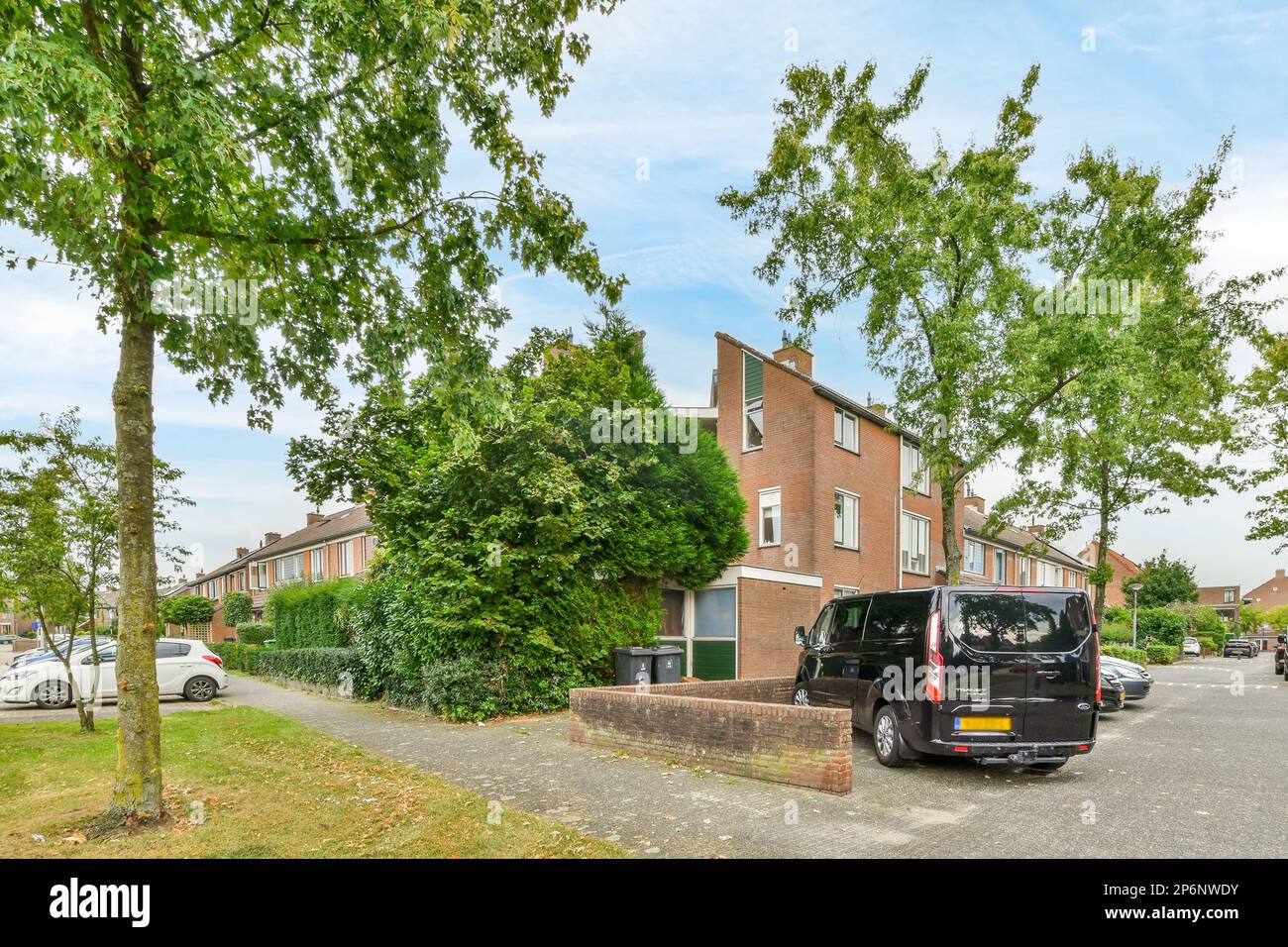 a street with cars parked on the side and houses in the back, some ...