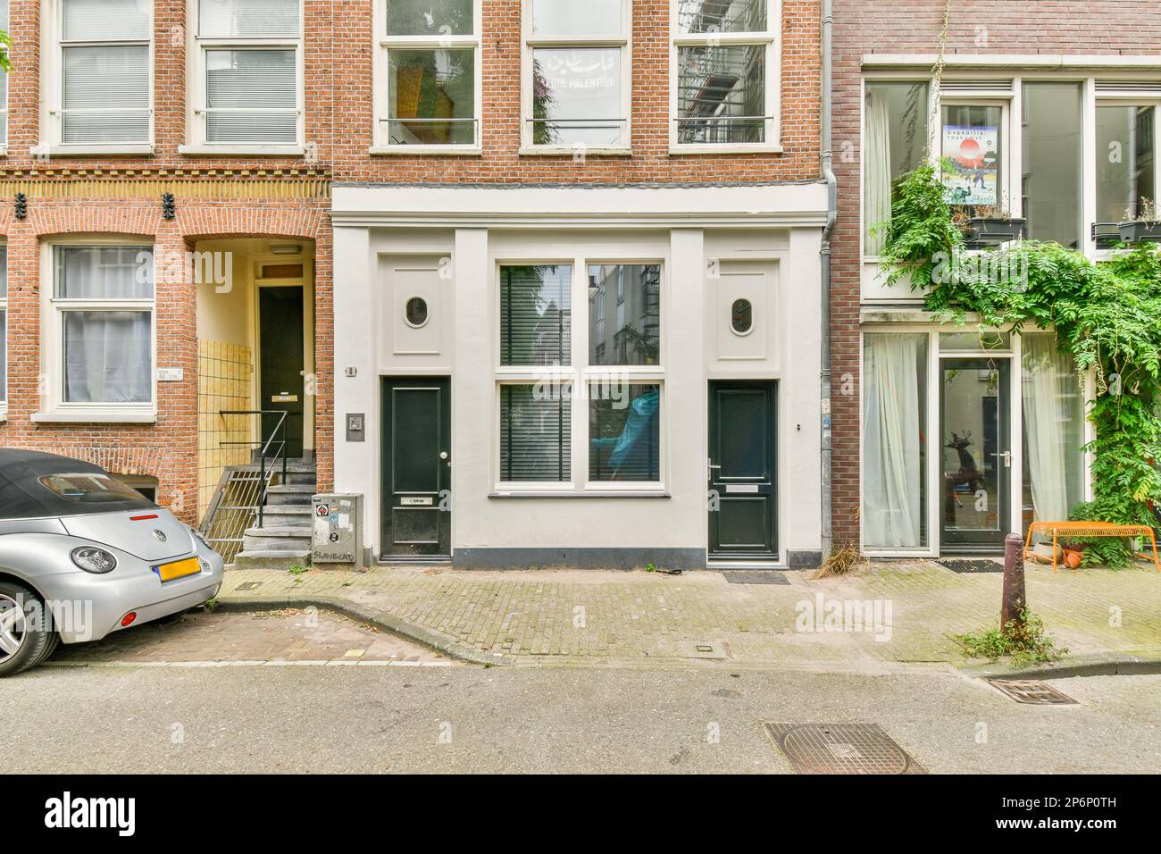 a car parked in front of a brick building with two windows on each side ...