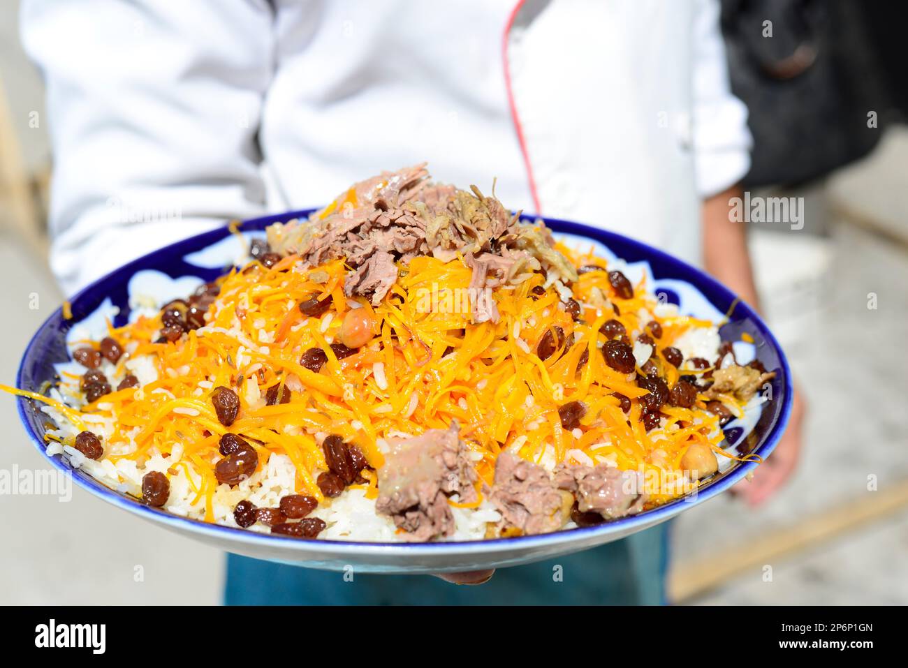 Plov is the national dish of Uzbekistan. An Uzbek man holding a plate ...
