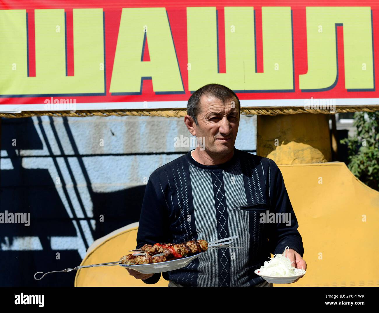 An Uzbek waiter holding a plate of meat skewers (Shashlik / kebab ) in ...