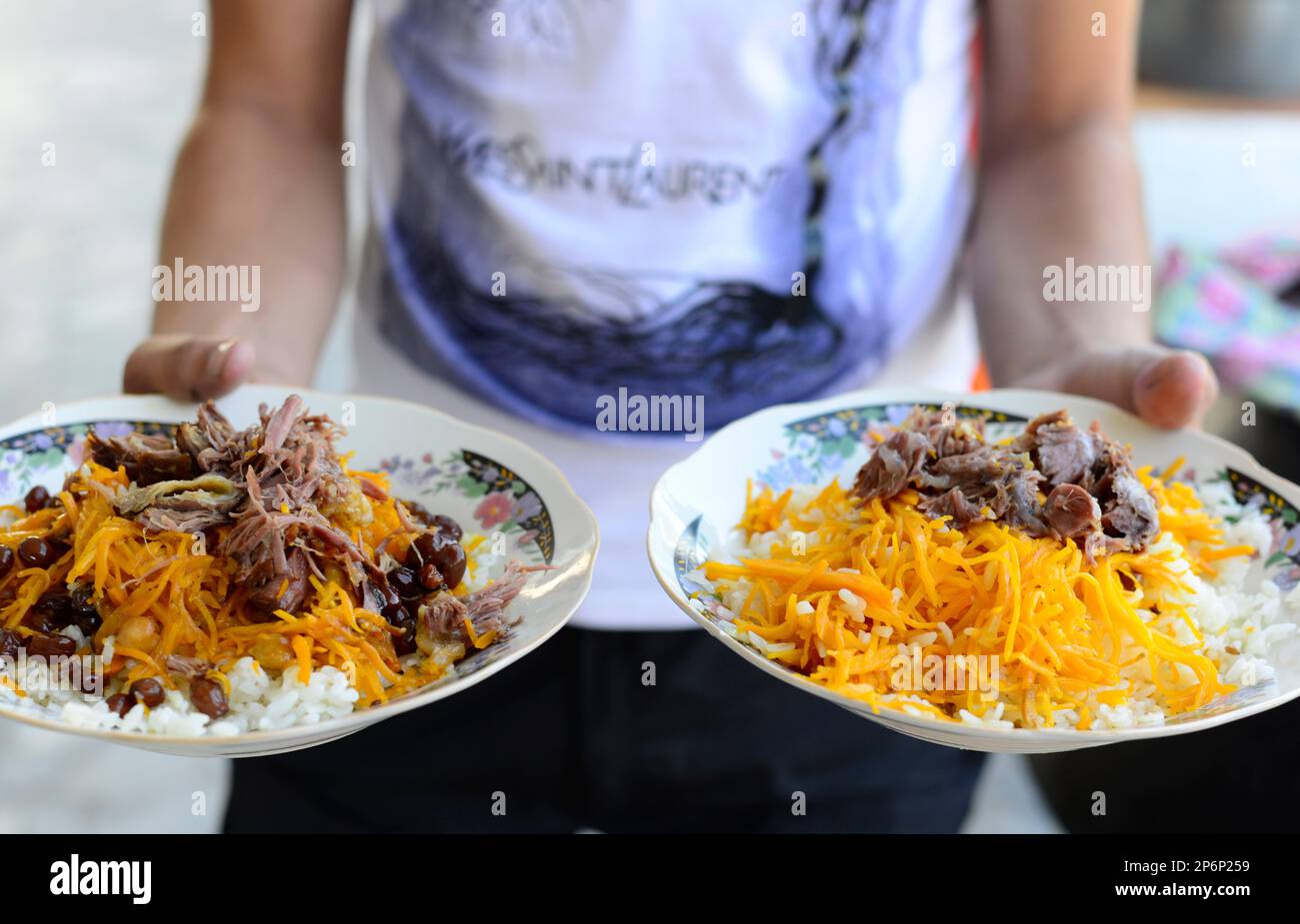 Plov is the national dish of Uzbekistan. An Uzbek man holding a plate ...