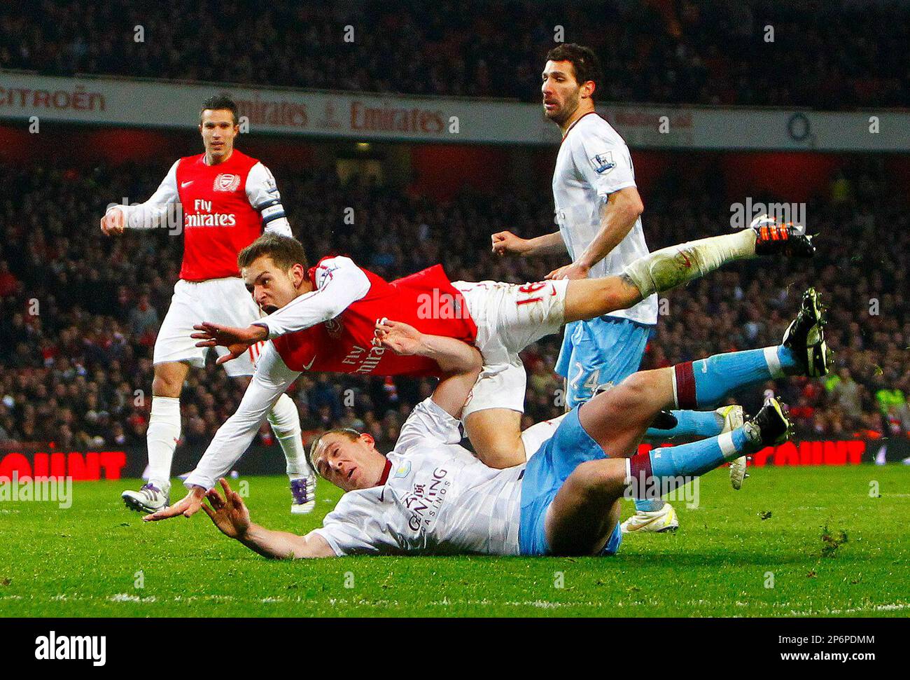 Richard Dunne of Aston Villa brings down Aaron Ramsey of Arsenal and ...