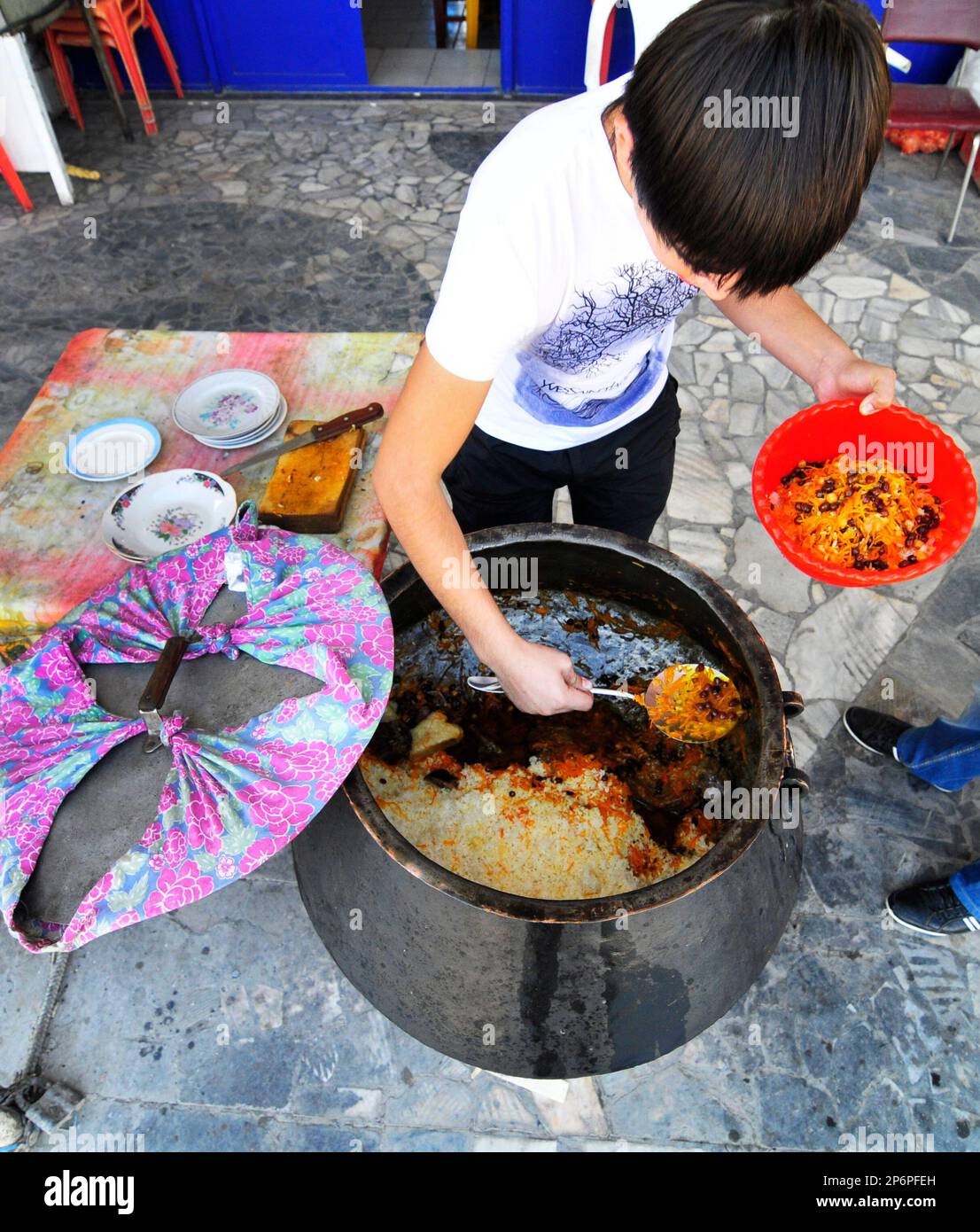 Plov is the national dish of Uzbekistan. An Uzbek man taking out Plov ...