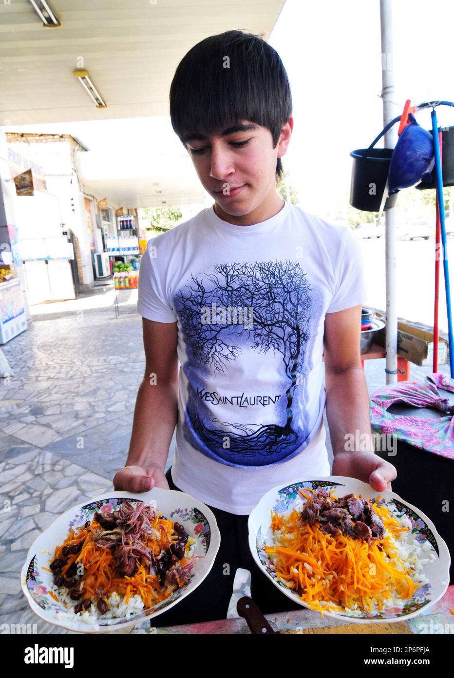 Plov is the national dish of Uzbekistan. An Uzbek man holding a plate ...