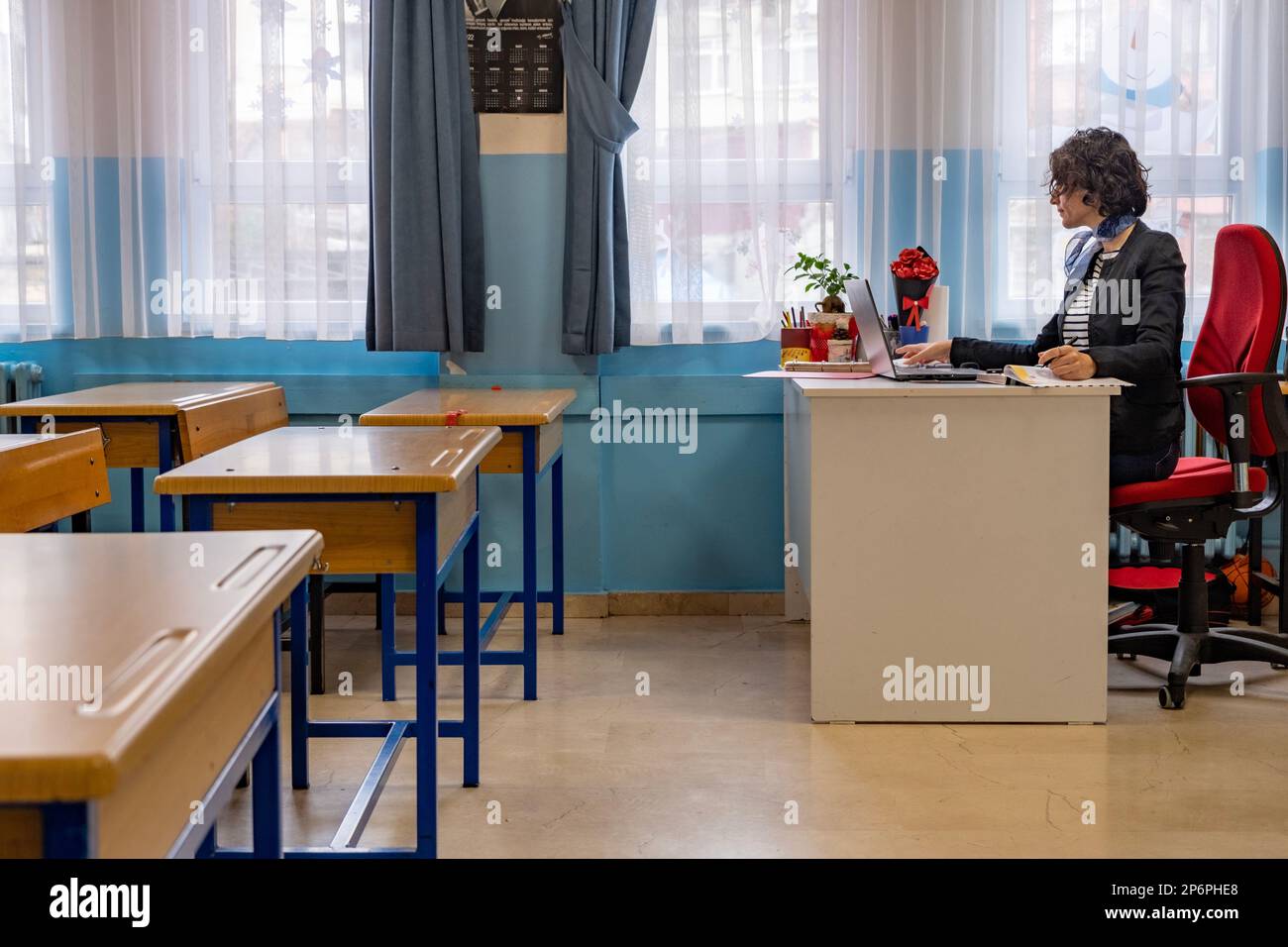 Mature female teacher writing notes in her notebook, side view. Lots of ...