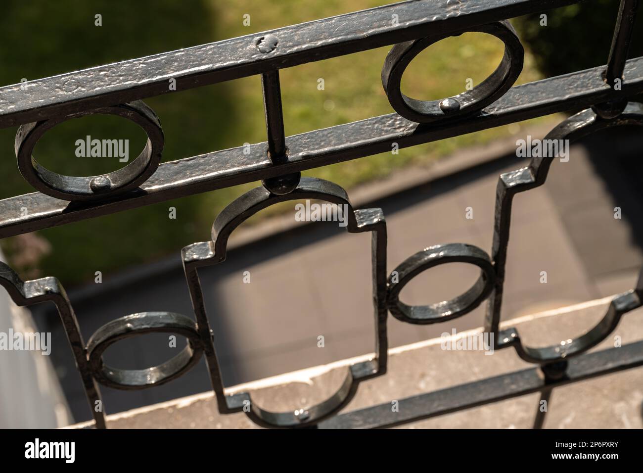 an iron fence with rings on it and green grass in the background is ...
